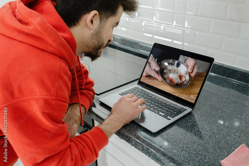 Cooking video, young adult putting laptop on counter in kitchen and ...
