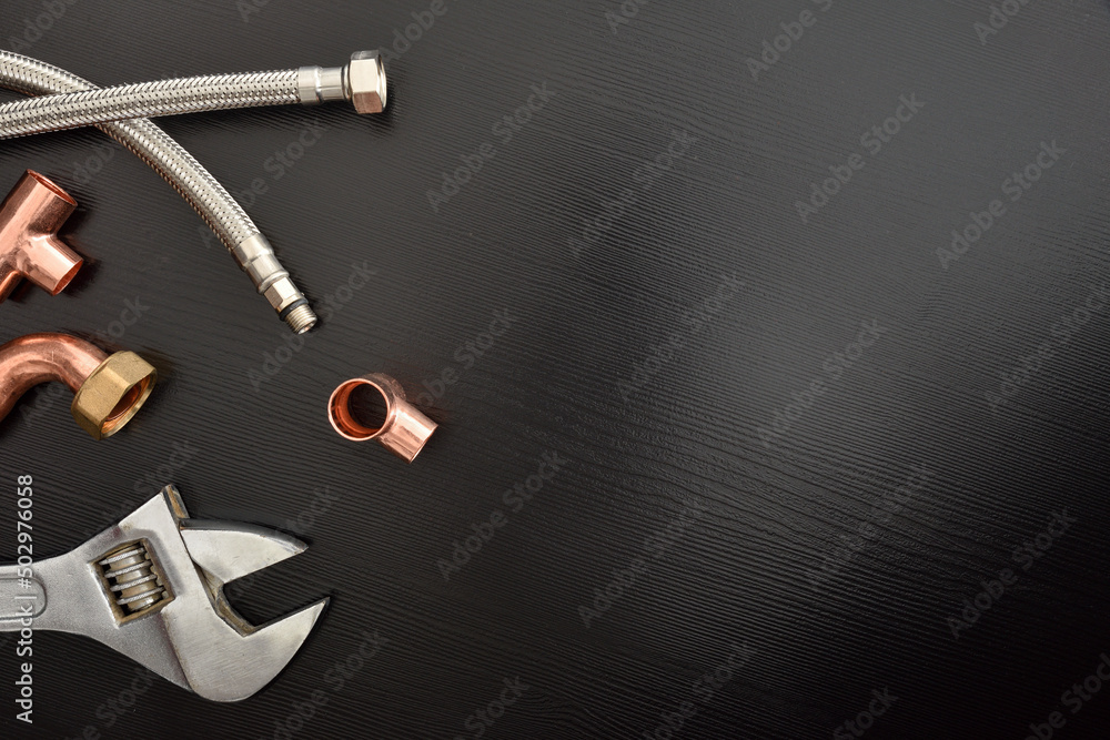 Plumbing conceptual background with wrench and pipes on black table ...