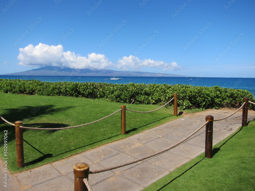 Concrete walkway towards the ocean, wooden stanchions with brown ropes ...