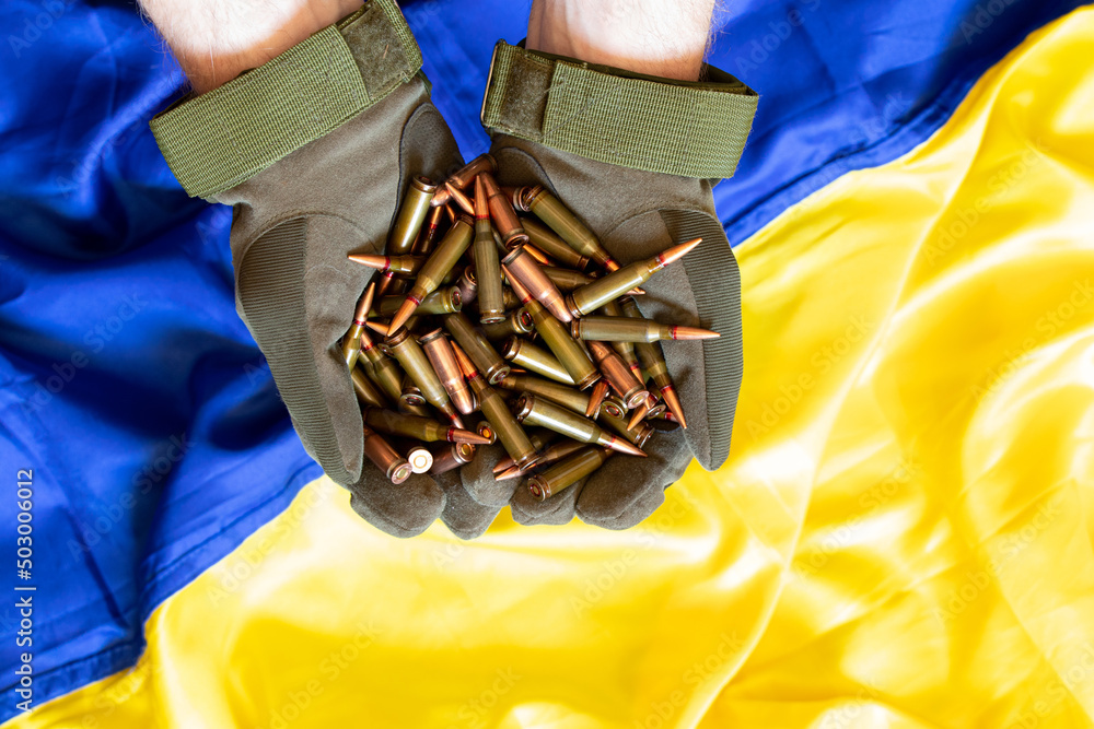 A Ukrainian soldier in gloves holds bullets from a machine gun against ...