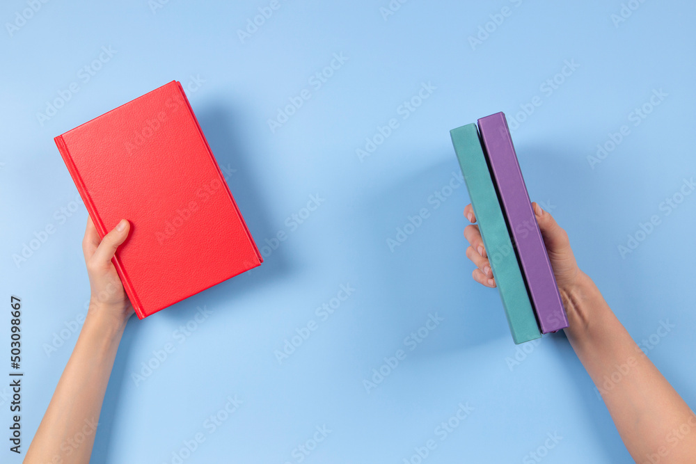 Fotka „Hands holding books over light blue background. Education, self ...