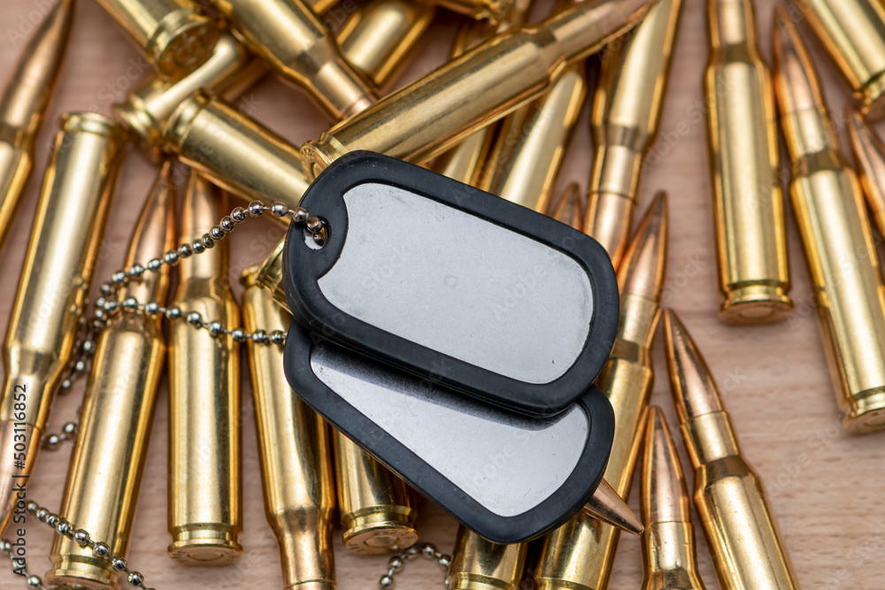 Army identification tokens lie on scattered yellow machine gun ...