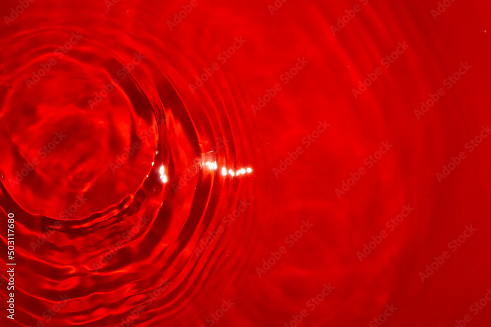 calm red water and a drop that made rings in the left corner of the ...