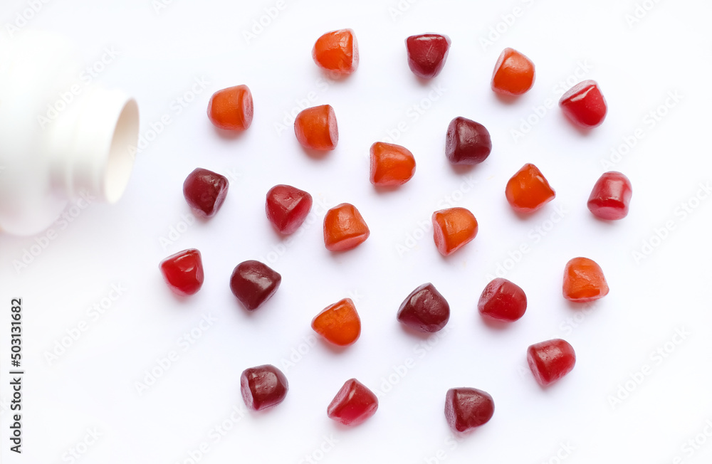 Group of red, orange and purple multivitamin gummies with the bottle ...