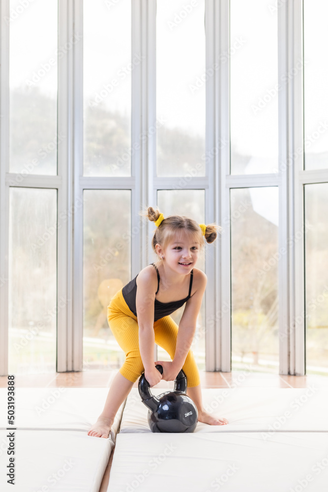 Cute little girl trying to lift kettlebell. Fitness fun Stock Photo ...