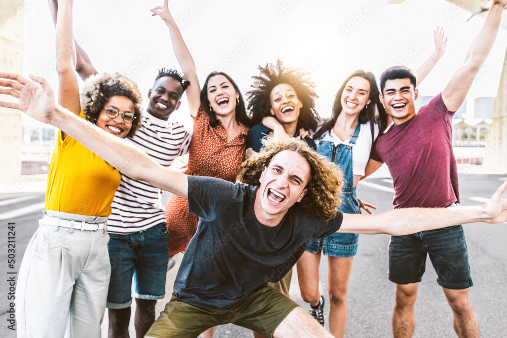Big group of happy friends stands on city street with raised arms ...