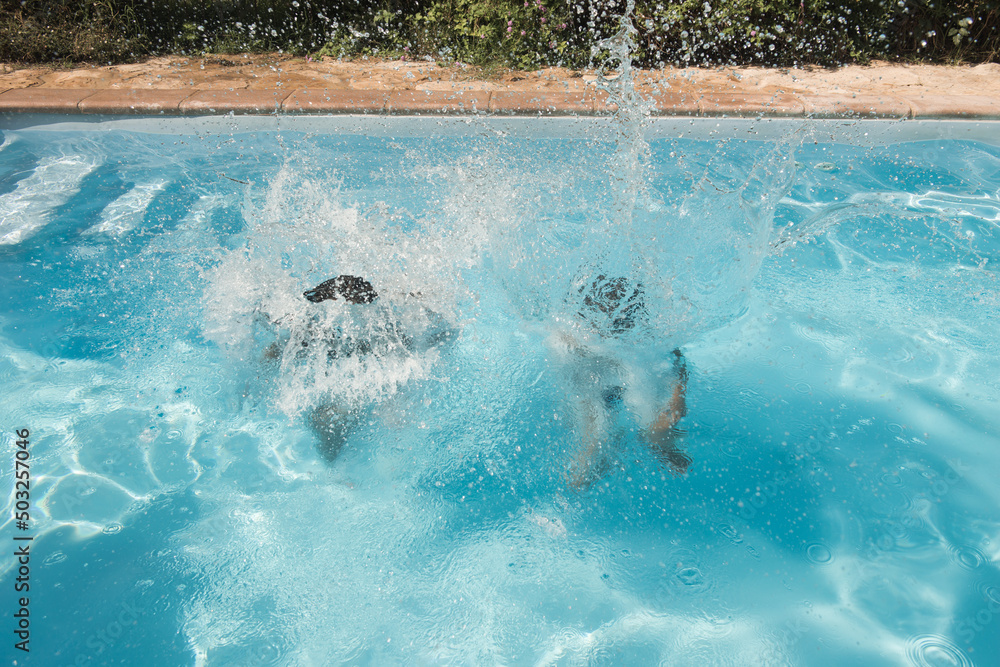 girl and boy jumping in the swimming the pool in summer with splash ...