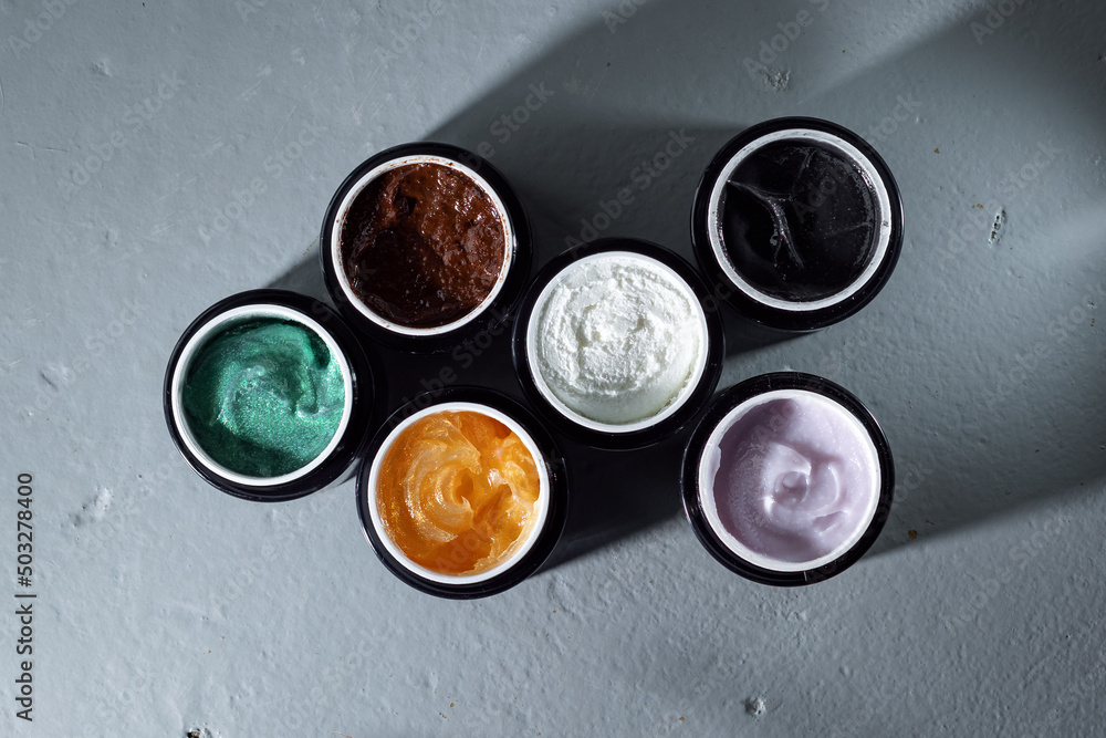 Body cream of different colors. Set with different body scrubs on gray ...