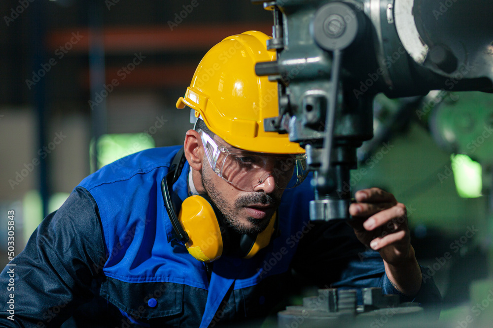 An engineer of mixed-American descent works with industrial machines in ...