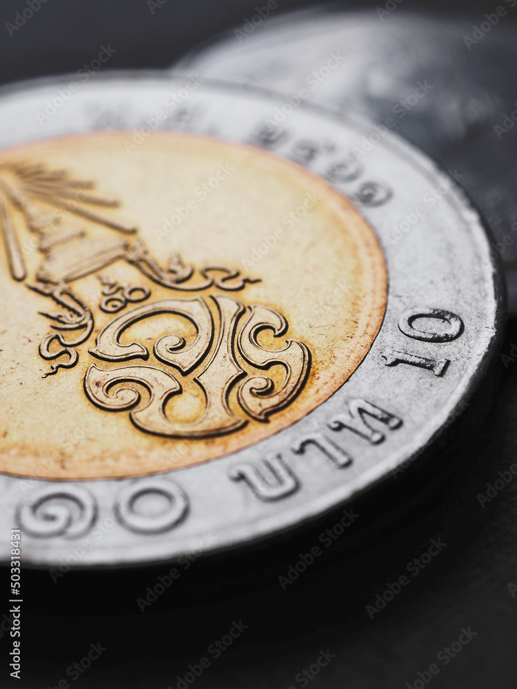 Translation: 10 baht Thailand. Thai coin of 10 baht lie on dark black ...