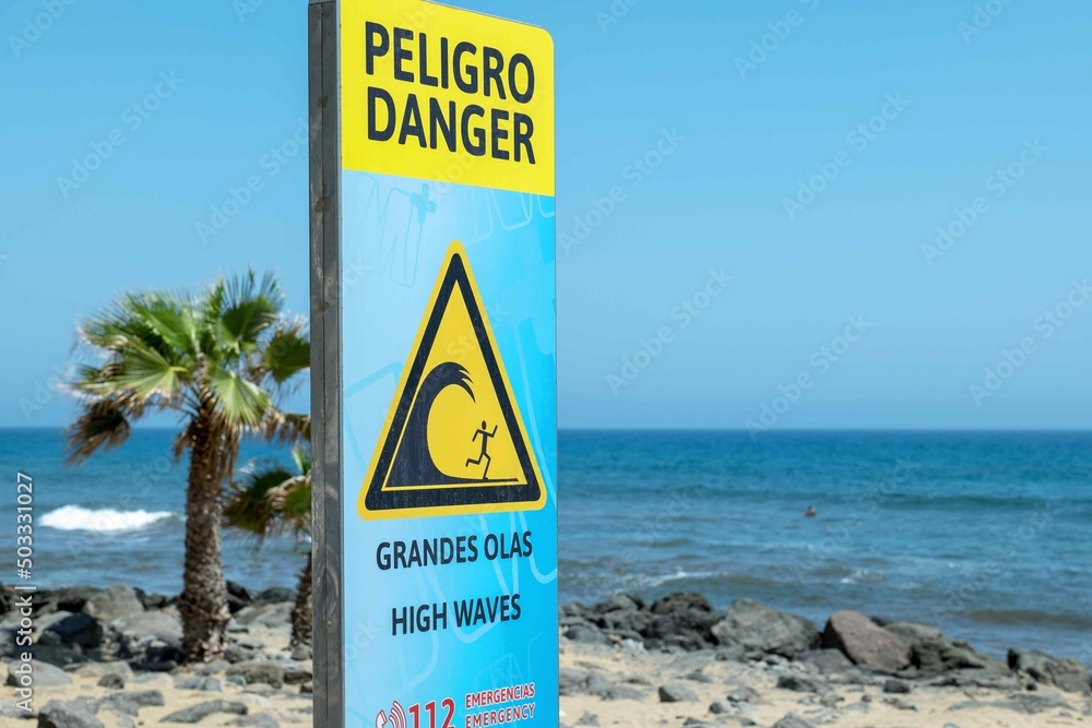 Warning sign on the beach in Spanish ("peligro" = danger) and English ...