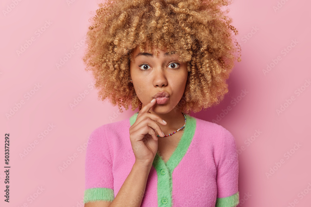 Surprised cute female model keeps lips folded widely opened eyes ...
