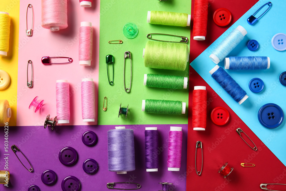 Thread spools, buttons and safety pins on color background Stock Photo ...