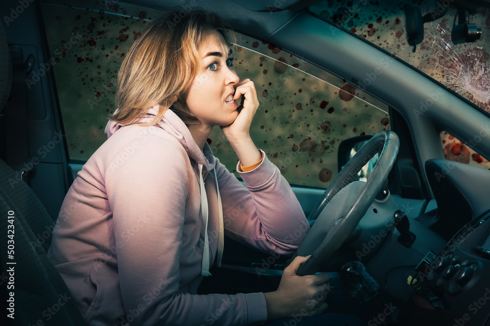 A scared nervous woman is sitting behind the wheel of a left-hand drive ...