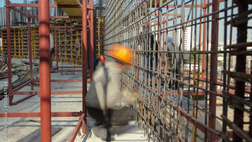 Construction workers working on steel rods used to reinforce concrete ...