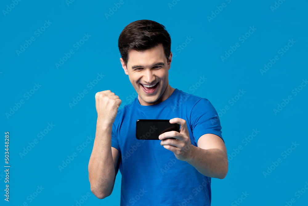 Handsome young male gamer clenching his fist with smiling face while ...