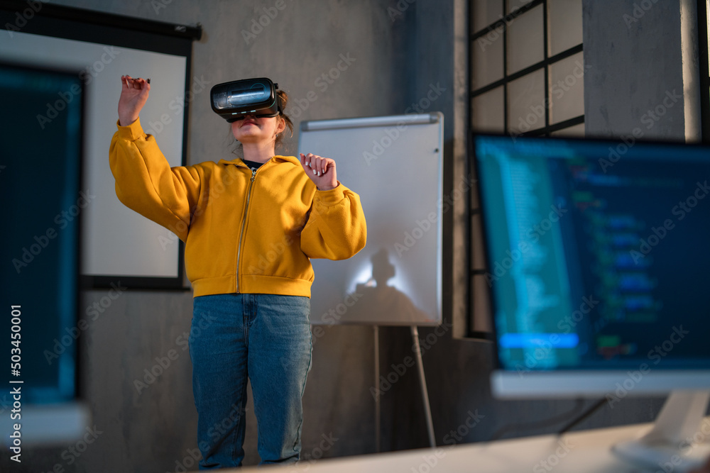 Schoolgirl wearing virtual reality goggles at school in computer ...