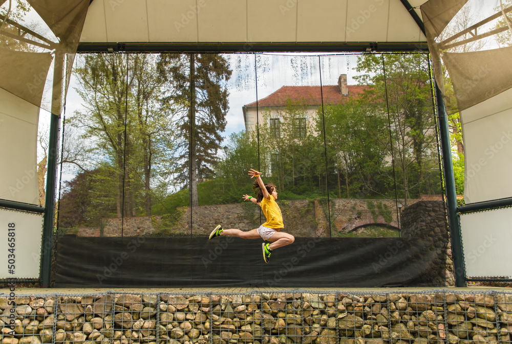 Little girl doing beautiful gymnastics jump against on stage outdoors ...
