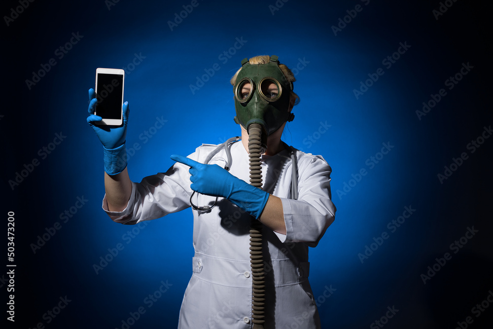 doctor woman in a gas mask points a finger at a mobile phone in her ...