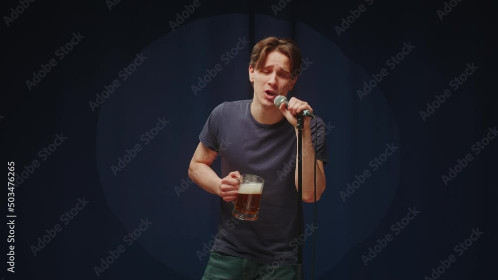 Vidéo Stock Drunk man singing on stage and drinking beer. Young guy in ...