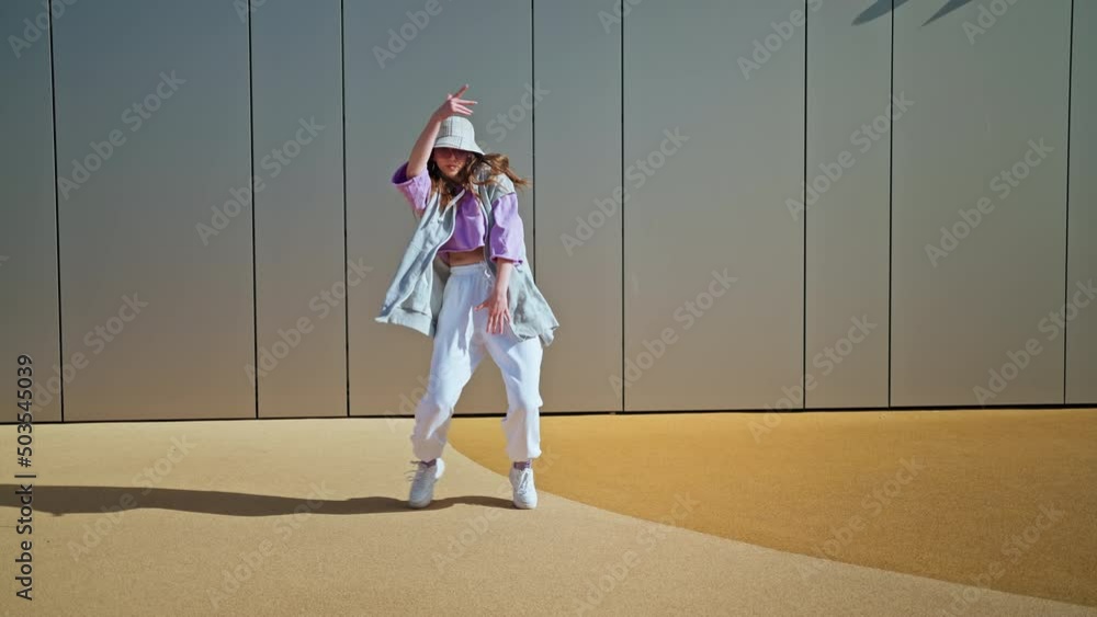 Young hip hop girl in oversize outfit wearing dancing into music ...