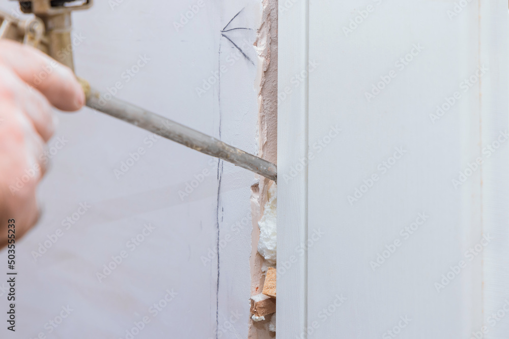 Handyman installing door with an mounting foam in a room in using ...