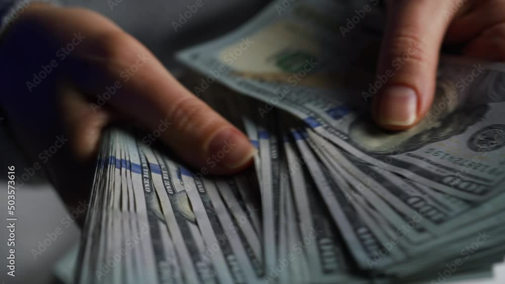 Hands checks US Dollar bills or counting in cash against the backdrop ...