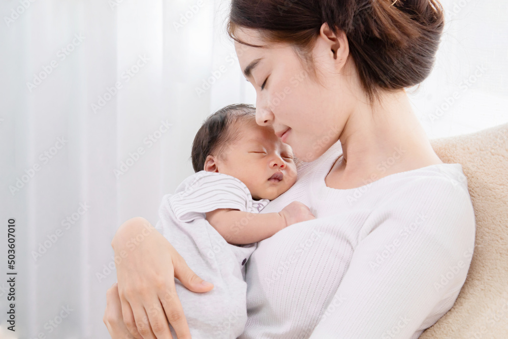 Asian mother holding her newborn in arm and sleeping together with love and care, adorable baby ...