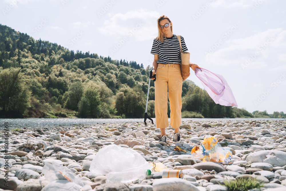Person help to keep nature clean up and pick up garbage. Young woman ...