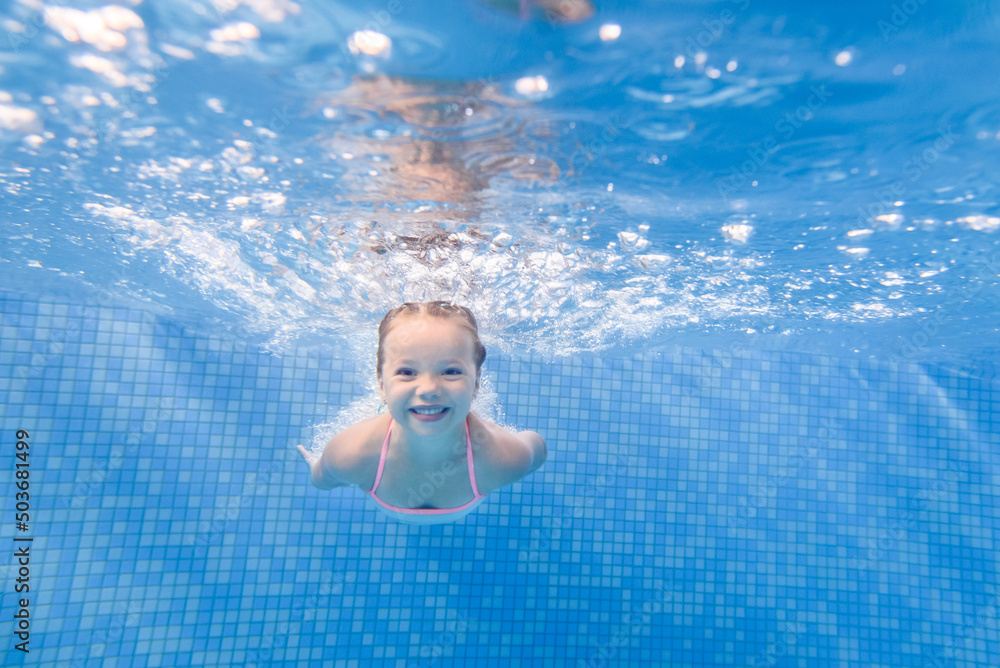 Little child girl swimming underwater in the paddling pool. Diving ...