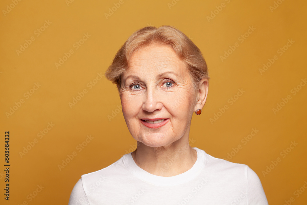 Cute friendly senior woman face on bright yellow studio background ...