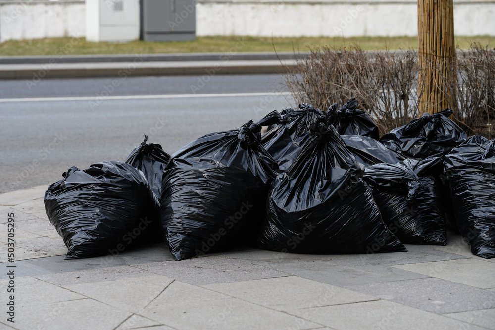 Pile of black garbage on the footpath at side road in big city ...