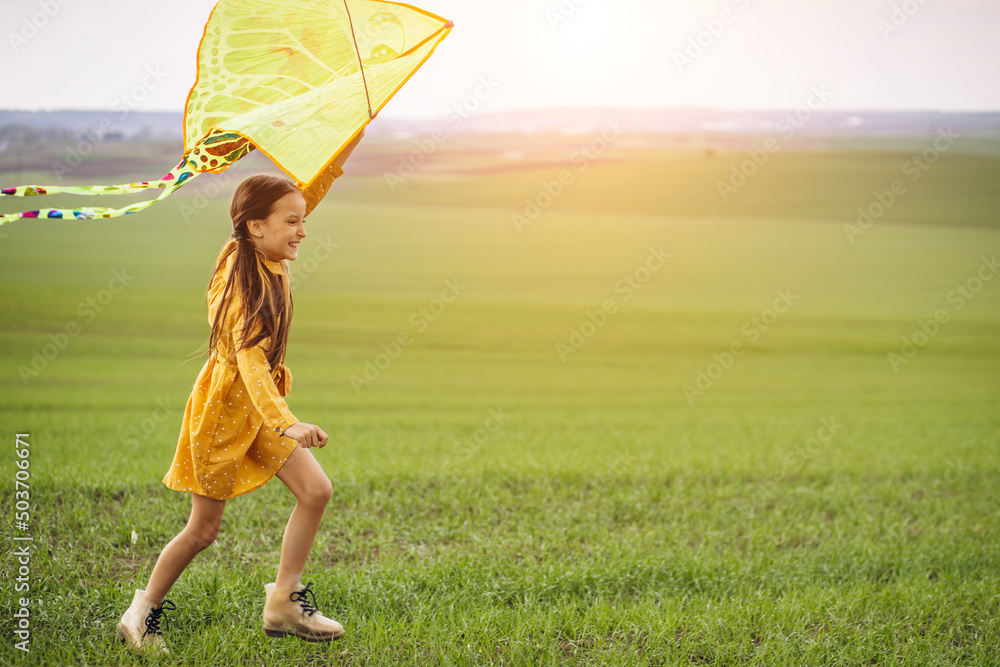 Foto de Little girl playing with colorful kite in the green field do ...