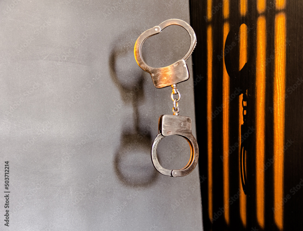 Handcuffs on the background of a concrete wall and a shadow from them ...