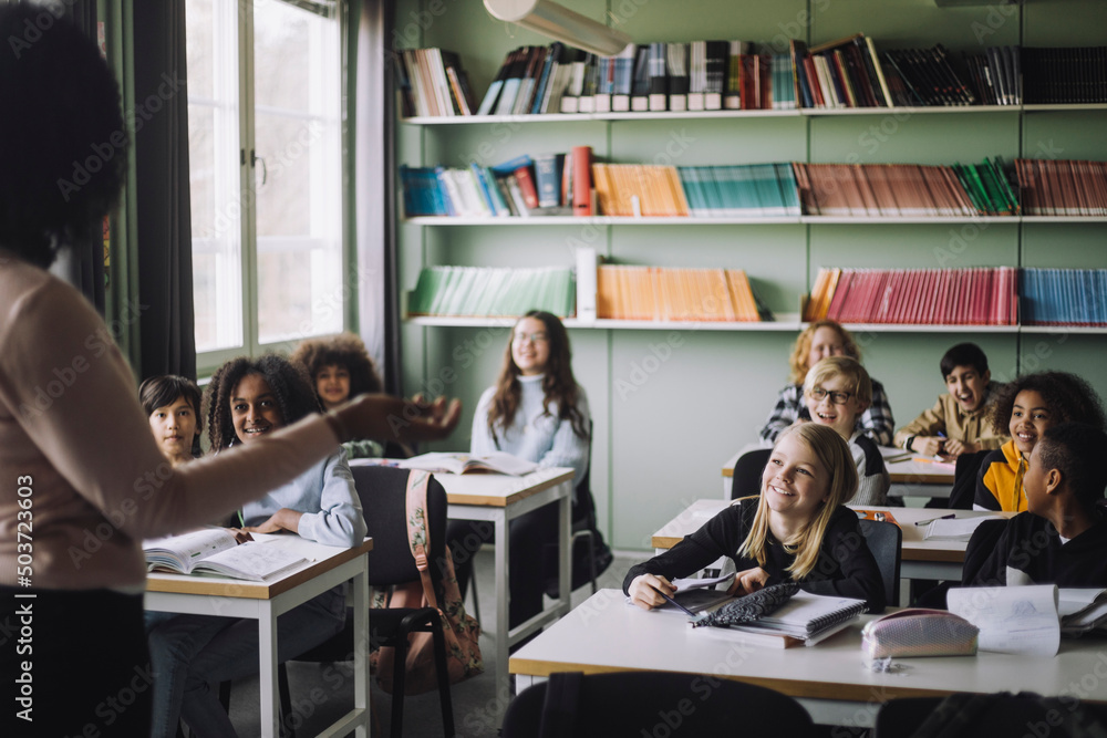 Happy students looking at teacher teaching in classroom Stock Photo ...