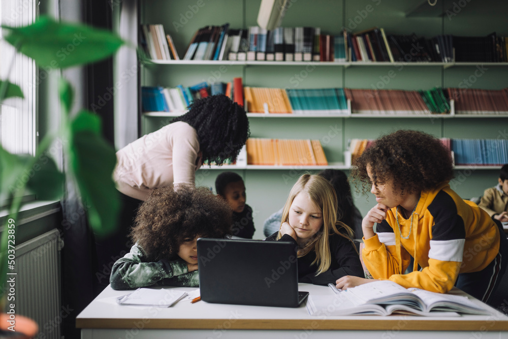 Multiracial students watching laptop while studying in classroom Stock ...