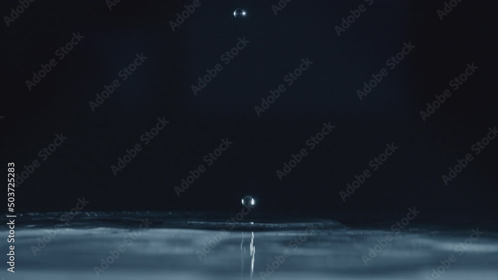 Ultra slow motion close up of water drop falling on a water surface ...