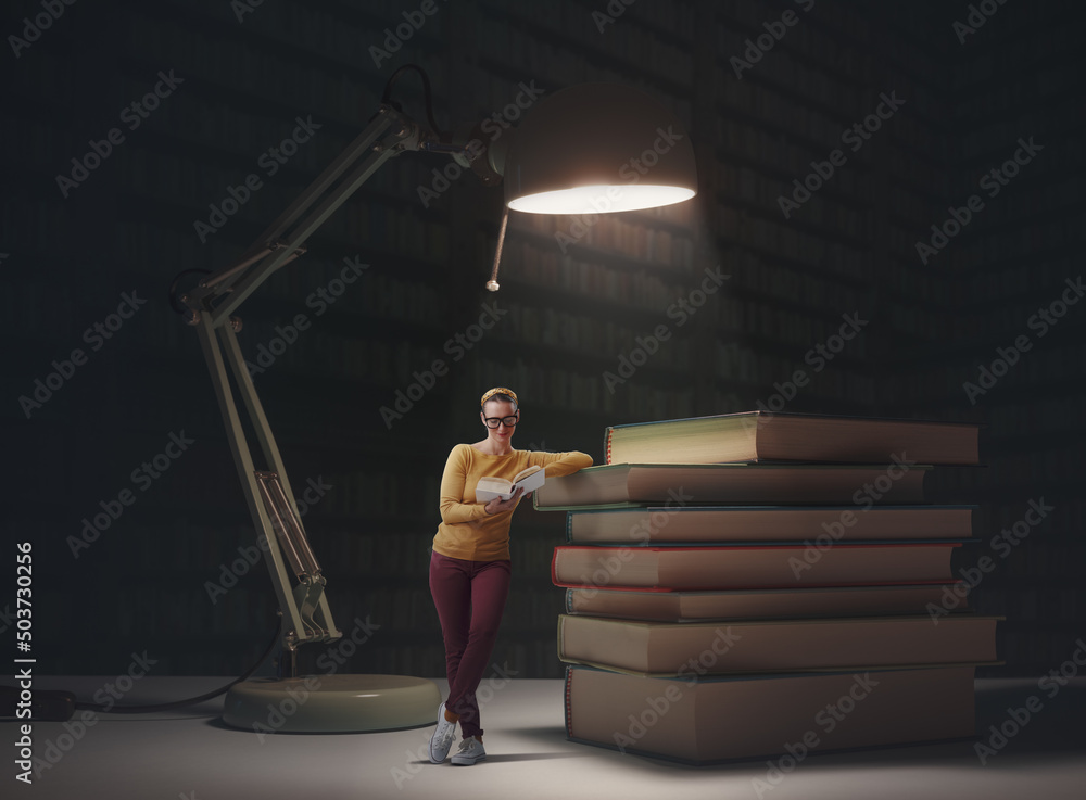 Tiny woman reading books in a dark library Stock Photo | Adobe Stock