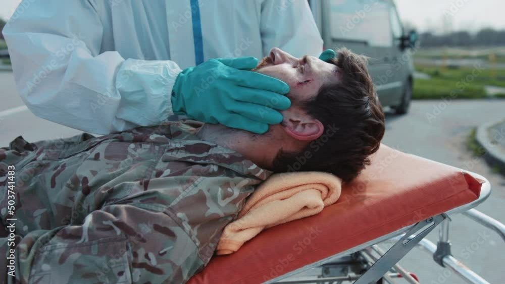 Doctor examining shrapnel wound on face of soldier wounded by artillery ...