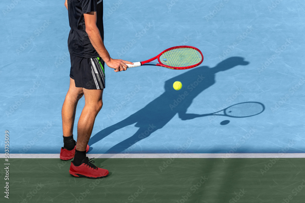 Tennis player bouncing ball near base line on blue hard court befor ...
