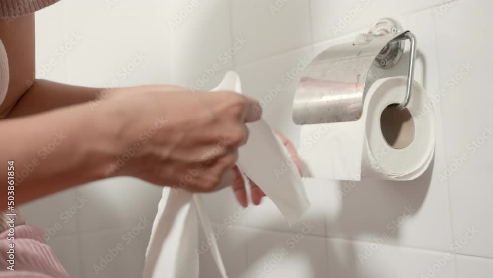 Closeup hand pulling toilet paper roll in holder for wipe, woman ...
