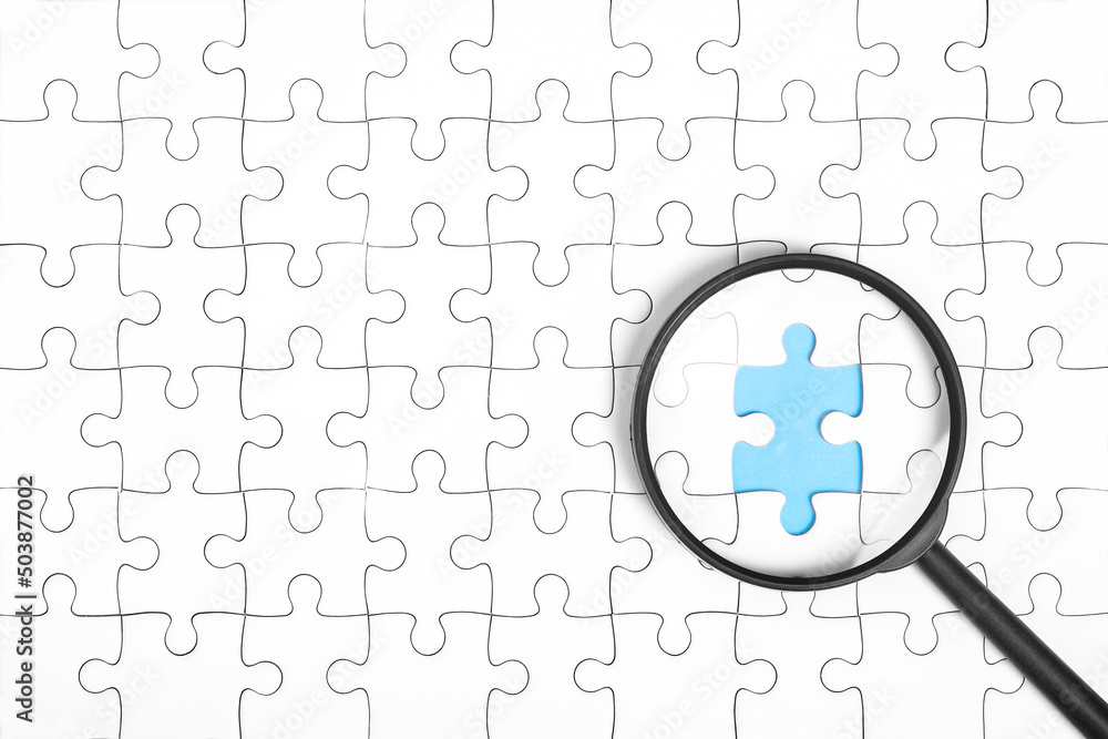 jigsaw puzzle pattern missing piece with a magnifying glass. Top view ...