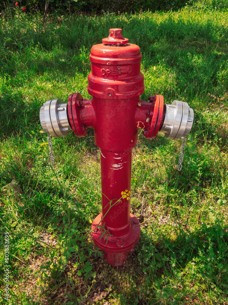 Red metal above ground water fire hydrant piping point against green ...