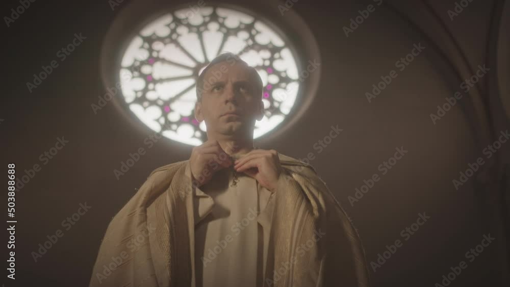 Low angle slowmo of Caucasian clergyman wearing long white vestment ...