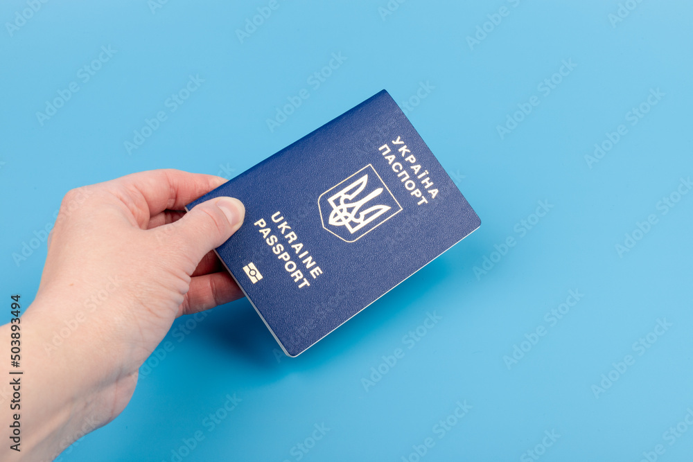 Passport of a citizen of Ukraine in a female hand on a blue background ...