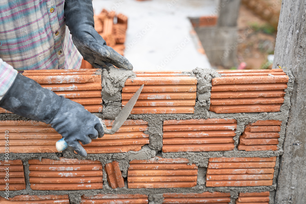 Construction worker installing bricks masonry bricklayer and adjusting ...