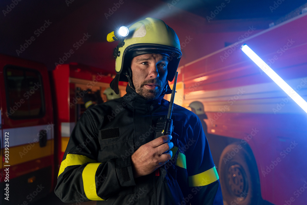 Firefighter talking to walkie talkie with fire truck in background at ...