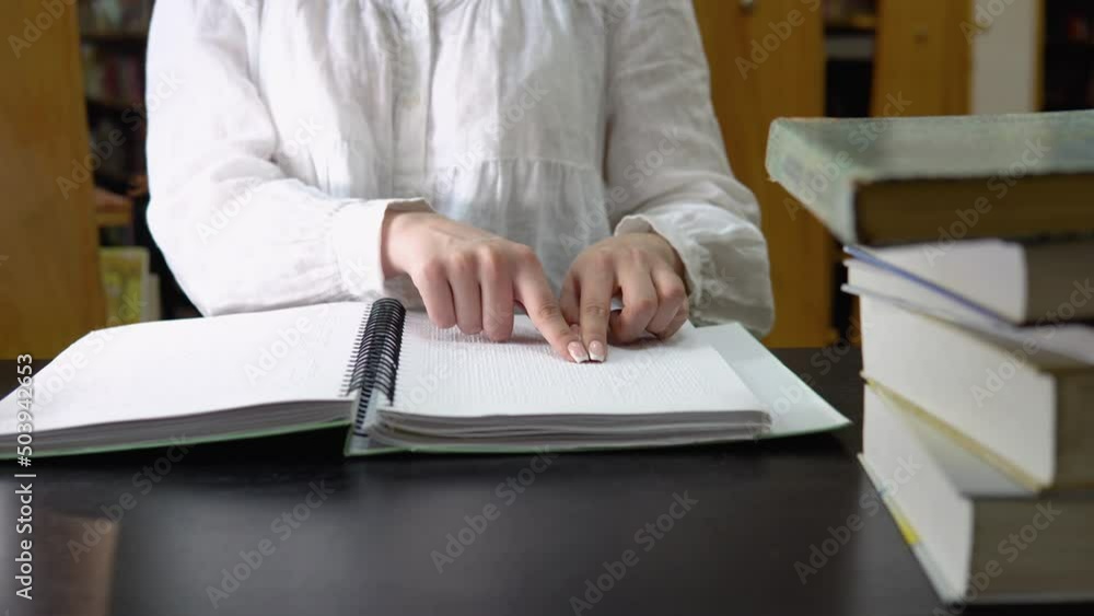 Blind girl reading a text of Braille in library. Braille is a tactile ...