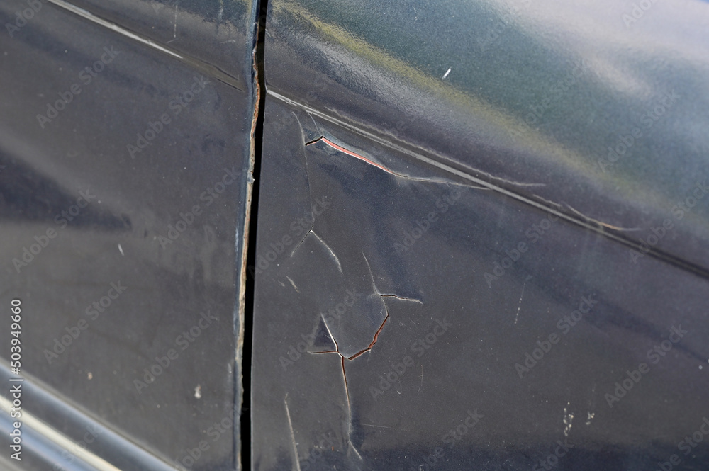 Cracked the surface of dark color on an old car parked on the parking ...