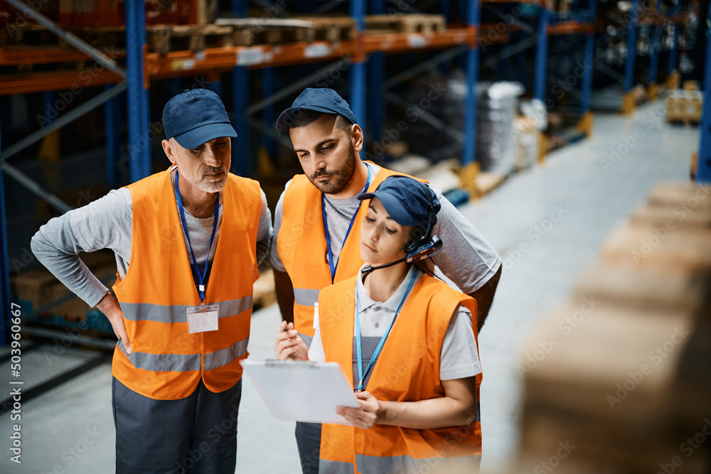 Group of warehouse workers going through checklist at storage ...